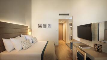 Quarto de hotel moderno com uma cama grande, uma escrivaninha, televisão de tela plana e um guarda-roupa.