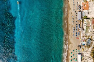 Praia particular, areia preta, espreguiçadeiras, guarda-sóis 