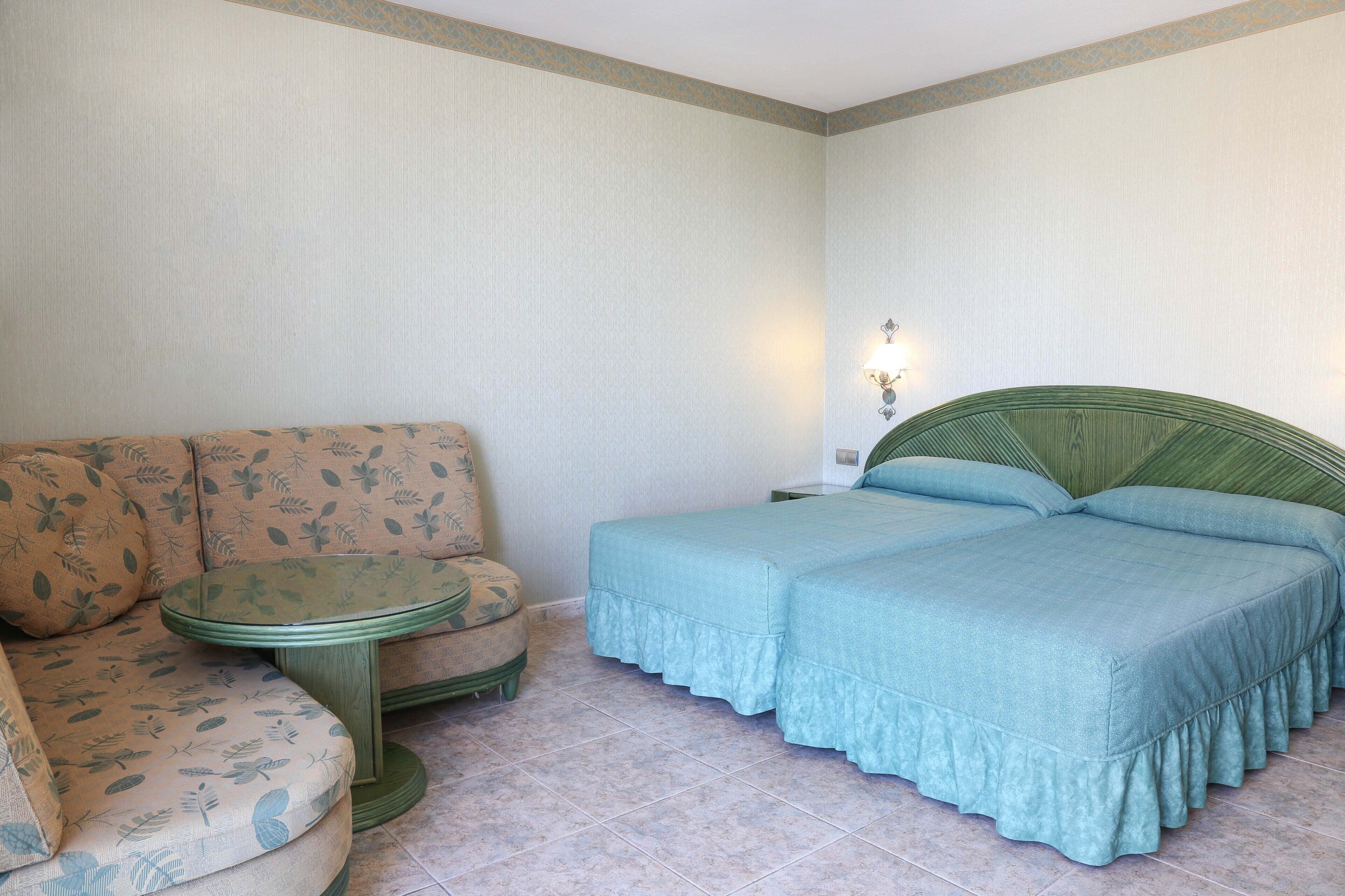 Um quarto com uma cama, um sofá e uma mesinha.