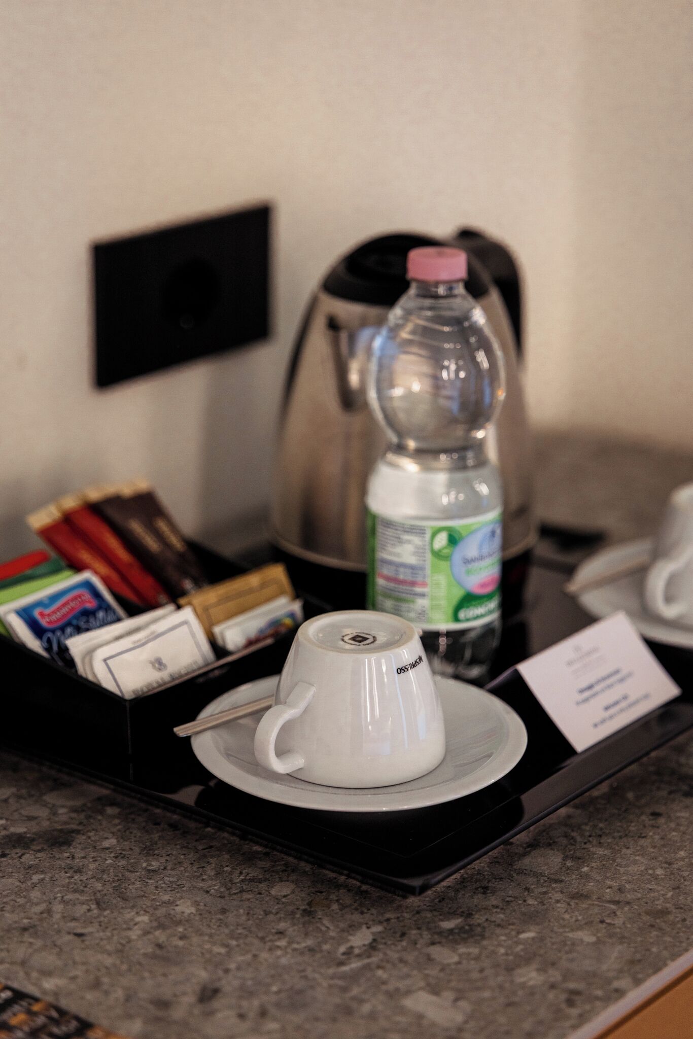 Uma estação de café com uma chávena branca, uma garrafa de água e vários pódios de café num tabuleiro.