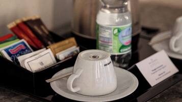 Uma estação de café com uma chávena branca, uma garrafa de água e vários pódios de café num tabuleiro.
