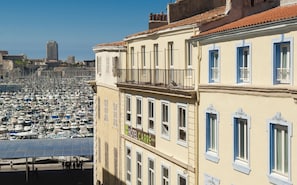 Hotel com varanda com vista para um porto cheio de barcos.