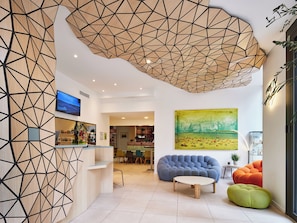 Um interior moderno com design geométrico na parede, uma pintura grande e uma área de estar com mesa redonda.