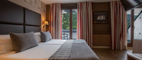 Quarto de hotel com uma cama grande, cabeceira, televisão e vista para o exterior.