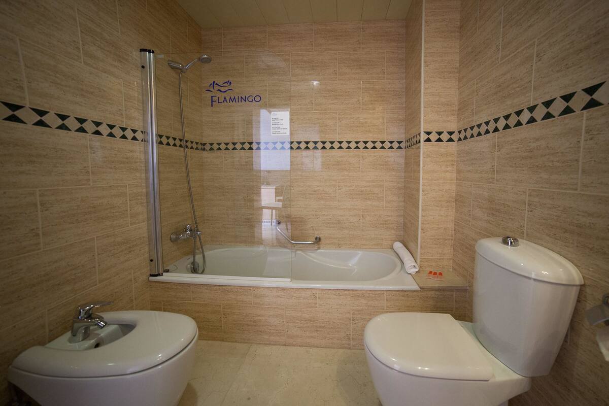 Casa de banho com cabine de duche, banheira e duas sanitas.