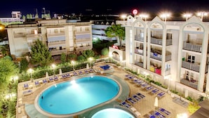 Um hotel com uma piscina grande cercada por espreguiçadeiras e um pequeno jacuzzi.