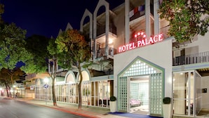 Um hotel com uma placa grande, várias varandas e uma entrada bem iluminada.