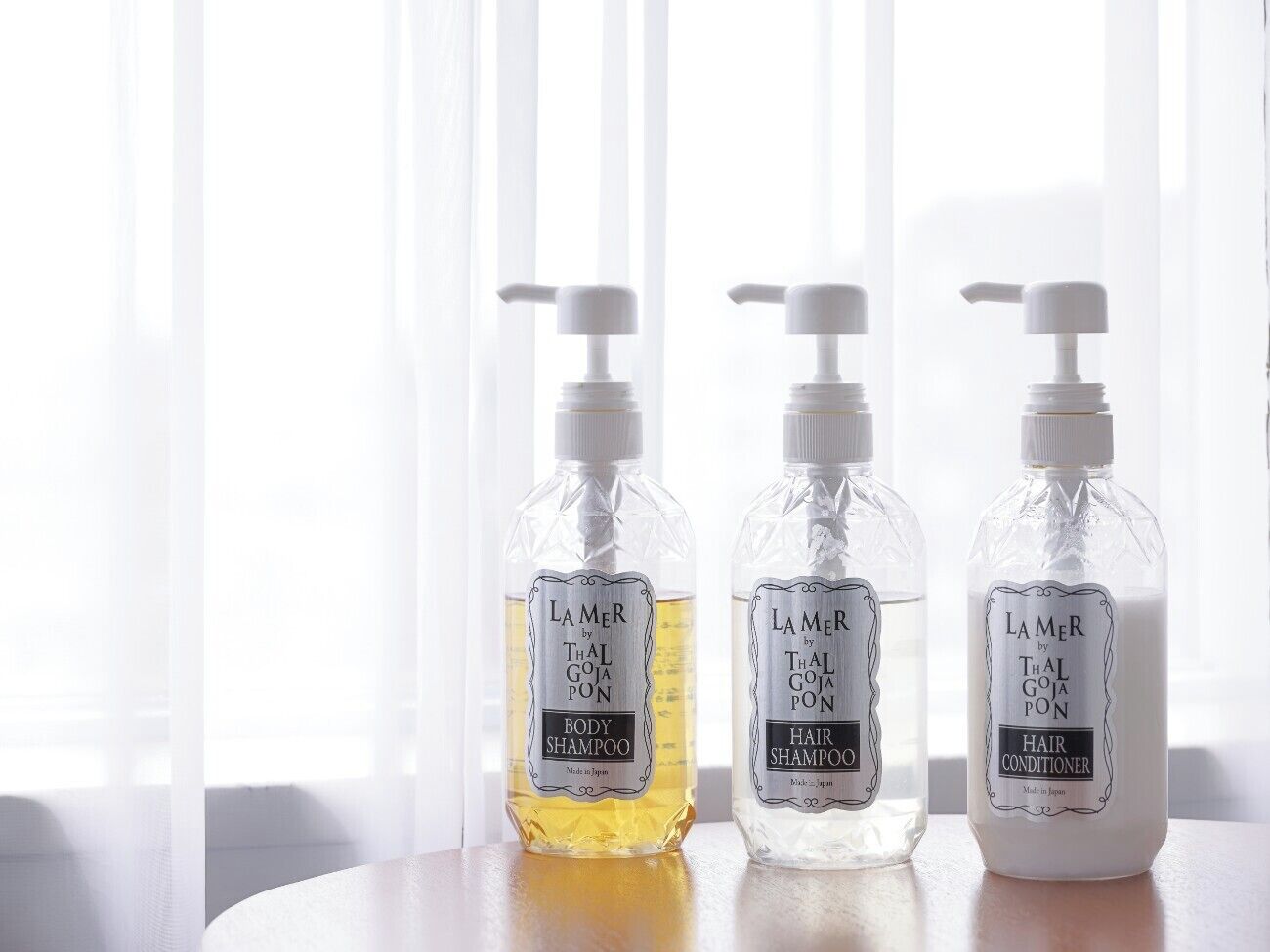 Três garrafas de shampoo e condicionador Lamer by Thai Goja Pon sobre uma mesa.