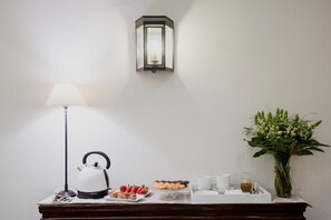 Uma mesa com chaleira, pastelaria e um vaso de flores.