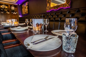 Um restaurante com uma mesa comprida posta para refeição, incluindo pratos, talheres e copos.