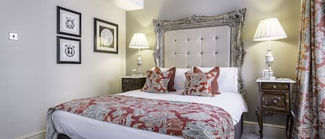 Quarto bem organizado com uma cama grande, duas mesas de cabeceira e um painel de cama clássico.