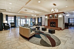 Um hall amplo com lareira, assentos confortáveis e um lustre moderno.