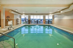 Piscina interior com água cristalina, cercada por janelas e equipada com equipamentos de segurança.
