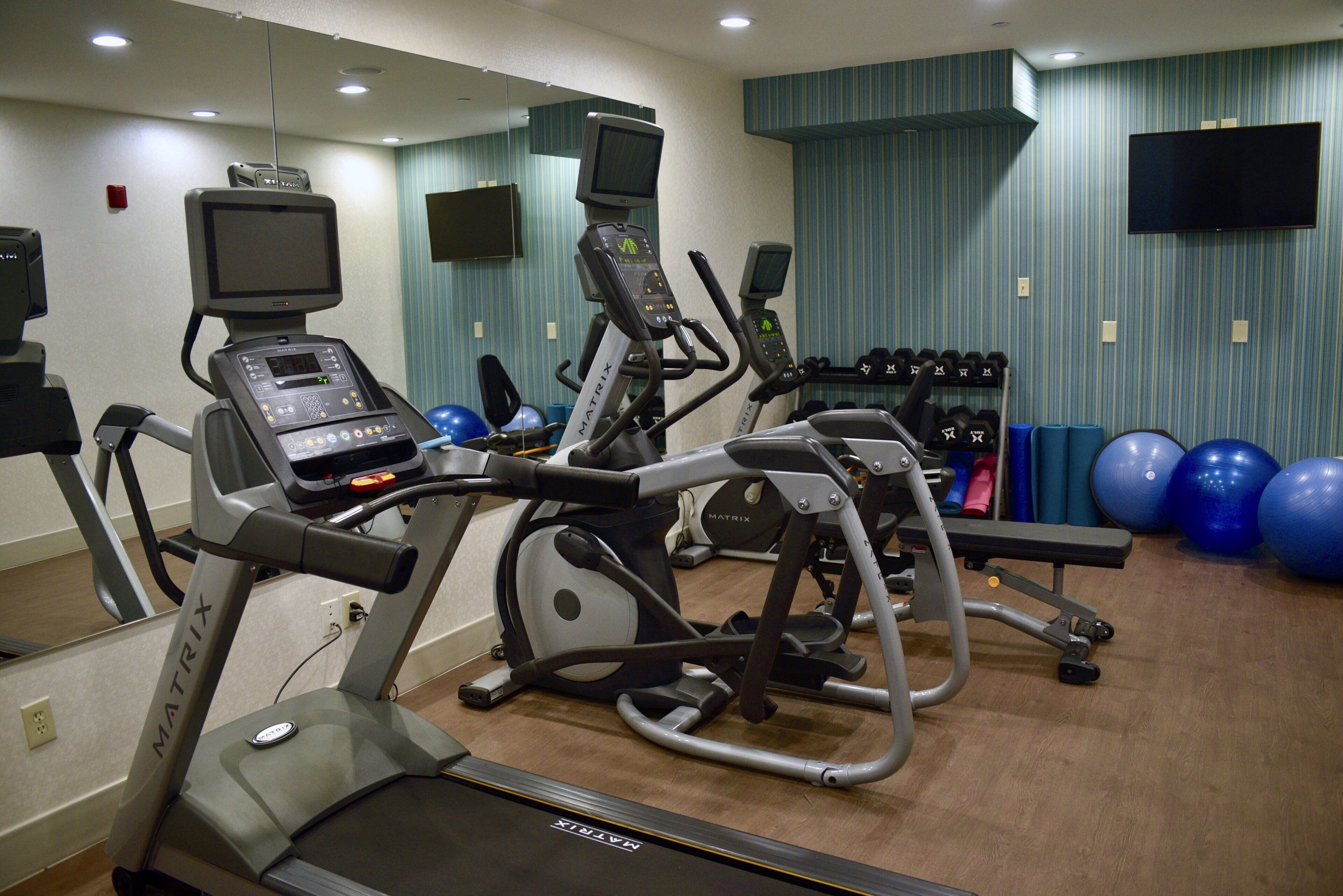 Academia com esteiras, elípticos e bolas de exercício.