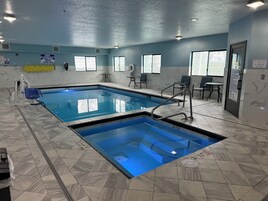 Piscina interna com água cristalina, paredes azulejadas e teto com iluminação embutida.