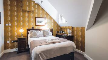 Quarto com cama, mesas de cabeceira, abajur e um quadro na parede.