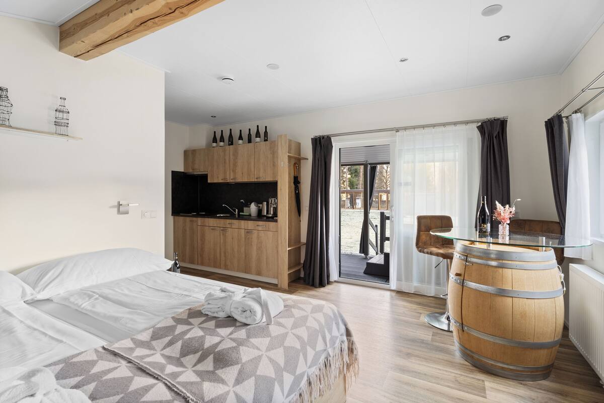 Quarto com cama, guarda-roupa de madeira, mesa de vidro e um barril.