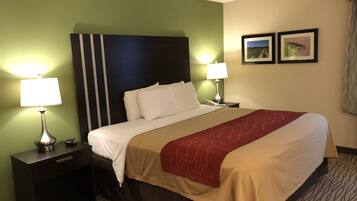 Quarto de hotel com uma cama, duas luminárias de cabeceira, um criado-mudo, um telefone e duas fotos emolduradas na parede.