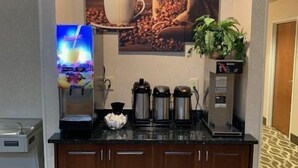 Uma área de cozinha com uma máquina de café, um jarro e uma cafeteira no balcão.