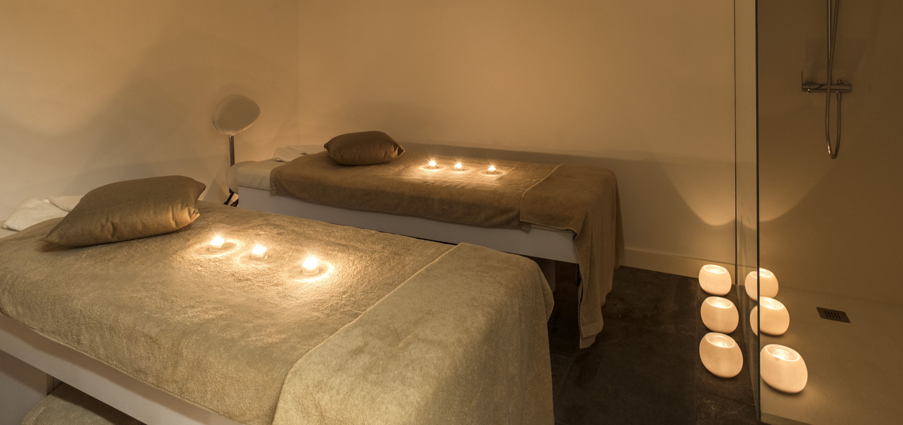 Quarto de hotel com duas camas, cada uma com um travesseiro e uma vela acesa.