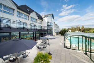 Um pátio de hotel com área de estar ao ar livre, piscina e uma área envidraçada.