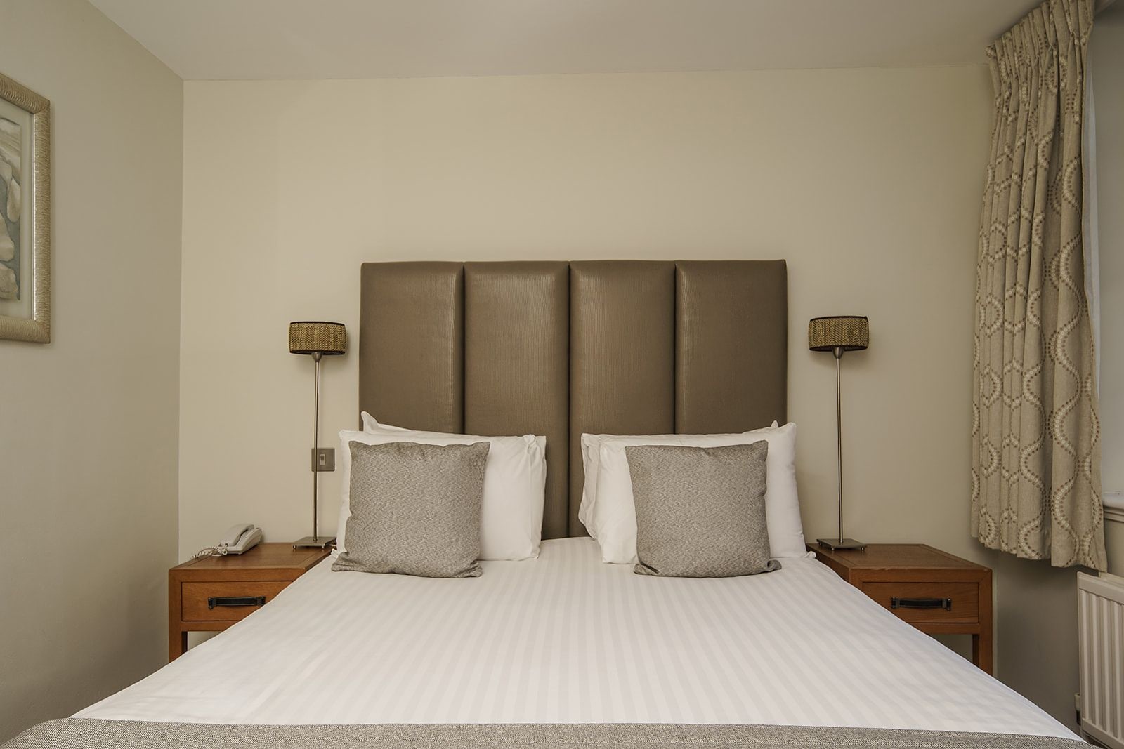 Quarto de hotel com uma cama grande, duas mesas de cabeceira e uma cabeceira.