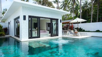Uma casa moderna com piscina, grandes portas de vidro e um terraço com cadeiras de descanso.