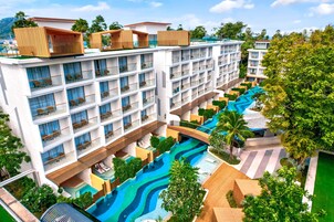 Um hotel com vários andares, varandas, piscina e vegetação exuberante.