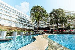 Um hotel com piscina, espreguiçadeiras e palmeiras.