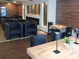 Restaurante moderno com assentos escuros, uma mesa de madeira e um vaso de planta.