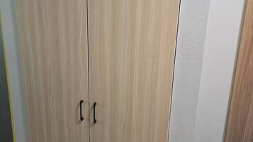 Um guarda-roupa com uma etiqueta a indicar 'wardrobe', um par de puxadores pretos e uma cadeira azul à direita.