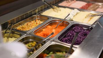 Buffet com diversas opções de comida em recipientes de metal.