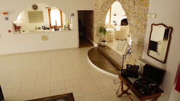Uma sala de estar espaçosa com lareira de pedra, mesa de centro de madeira e um espelho grande.