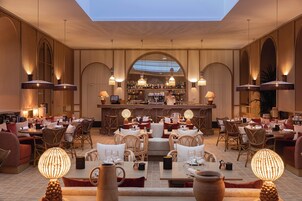 Um amplo hall de hotel com várias áreas de refeições, um bar e uma claraboia.