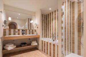 Uma casa de banho moderna com lavatório duplo, um espelho grande, chuveiro com porta de vidro e porta-toalhas.