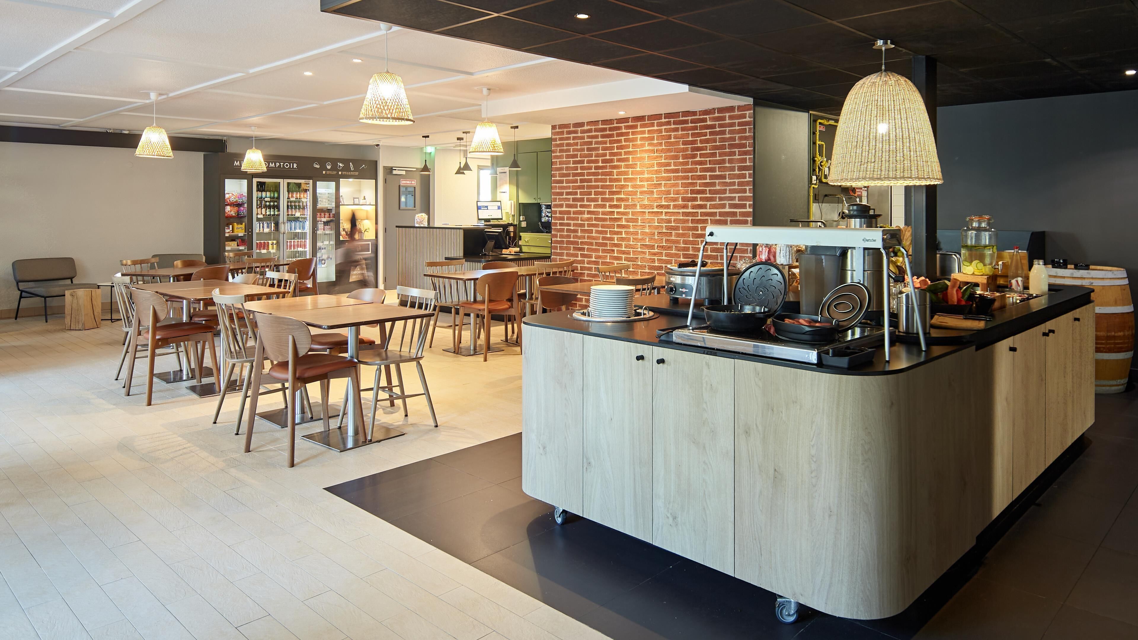 Um café moderno com balcão central, mesas e cadeiras de madeira e luminárias pendentes.