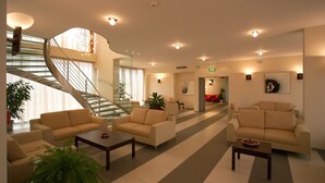 Um hall amplo com escadaria central, vários espaços de estar e uma grande planta.