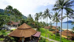 Um resort com bangalôs de telhado de palha, piscina e vista para o oceano.