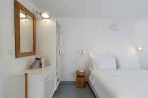 Quarto com cama, abajures, espelho, penteadeira e uma pequena mesa com livros.