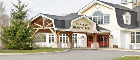 Chateau Beauvallon, um edifício grande com entrada notável, varanda coberta e placa com seu nome.
