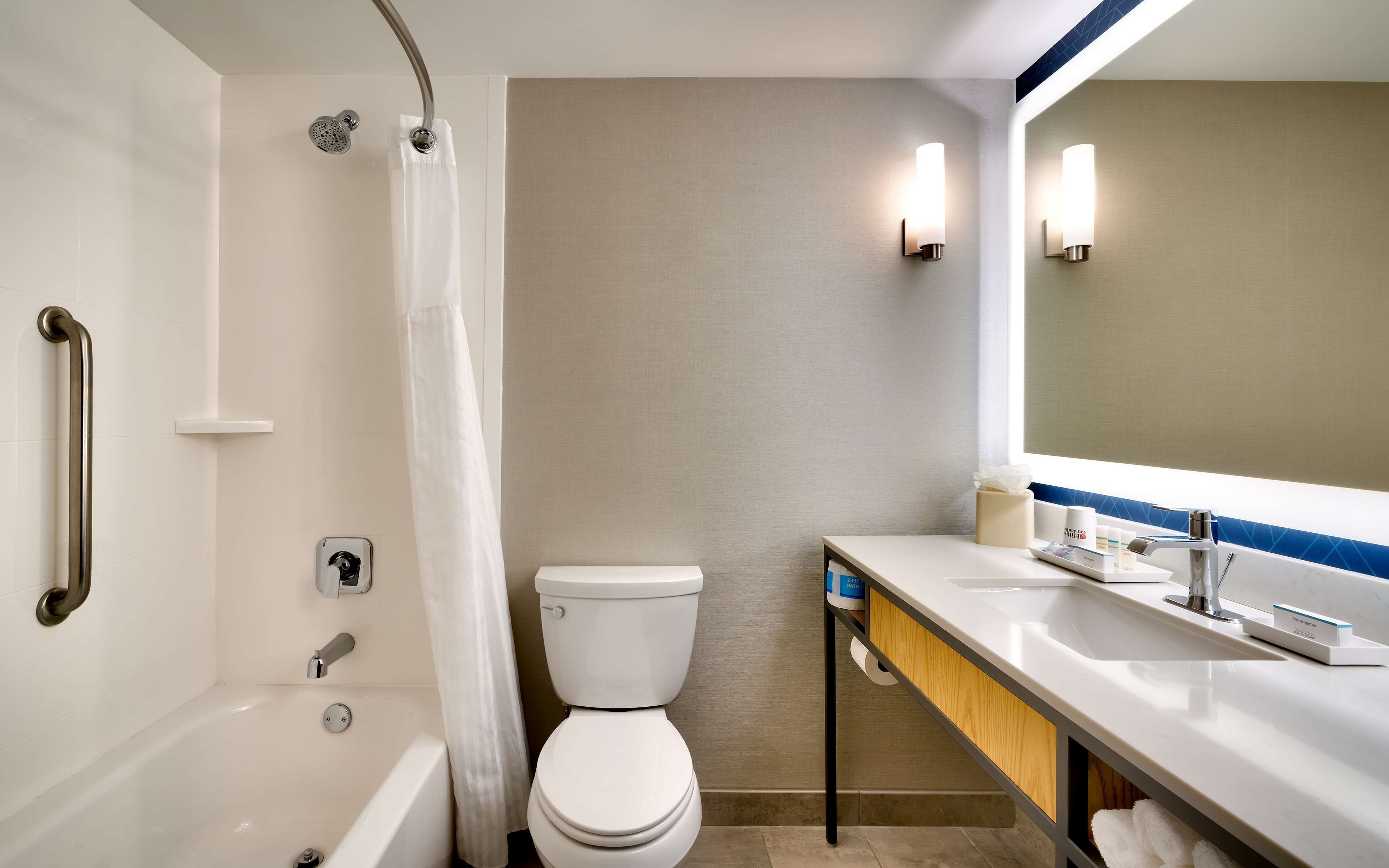 Uma casa de banho moderna com banheira, sanita e lavatório com espelho.