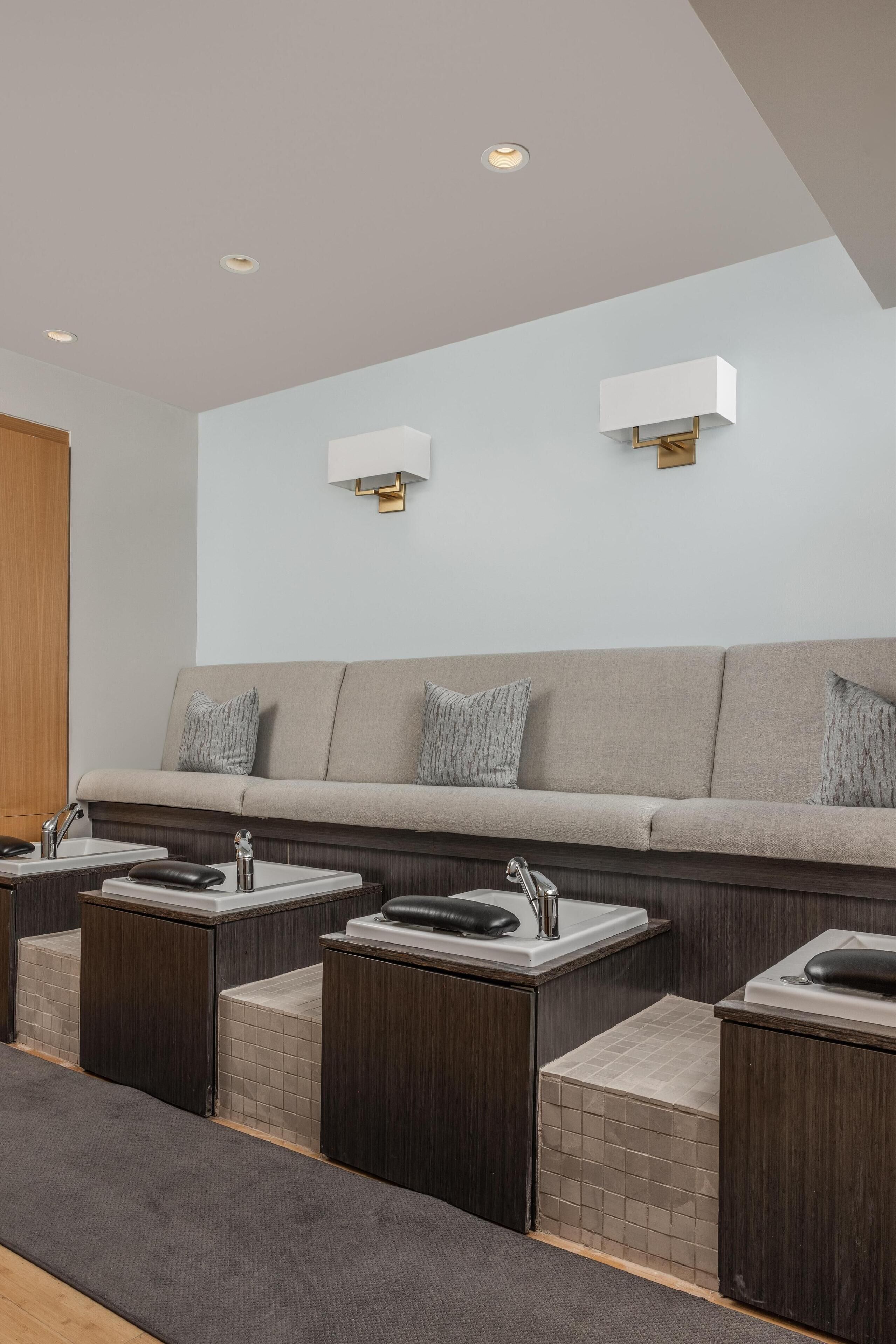Uma área de spa moderna com sofá, várias pias e iluminação embutida.