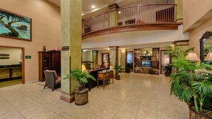 Um hall amplo com balcão de recepção, área de estar e escadas para um andar superior.
