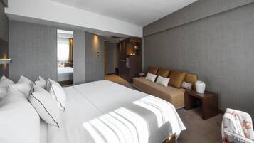 Quarto de hotel moderno com uma cama grande, um sofá, uma mesinha e um espelho.