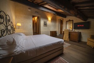 Quarto com cama, luminárias de cabeceira, televisão exibindo 'NETFLIX', um armário de madeira e um espelho.