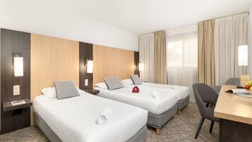 Quarto de hotel com duas camas, uma mesa e uma cadeira.