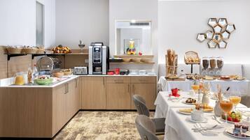 Disposição moderna para o pequeno-almoço, com uma máquina de café, fruteira e alimentos para o pequeno-almoço numa bancada.
