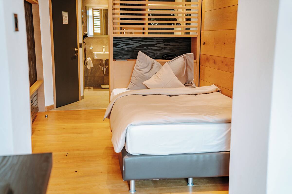 Quarto com cama, cabeceira de madeira e piso de madeira.