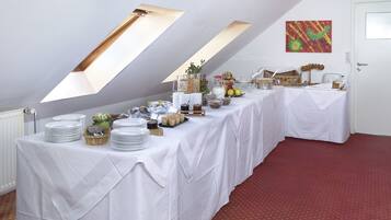 Uma sala de banquetes com mesas brancas, tapete vermelho e teto alto com claraboias.