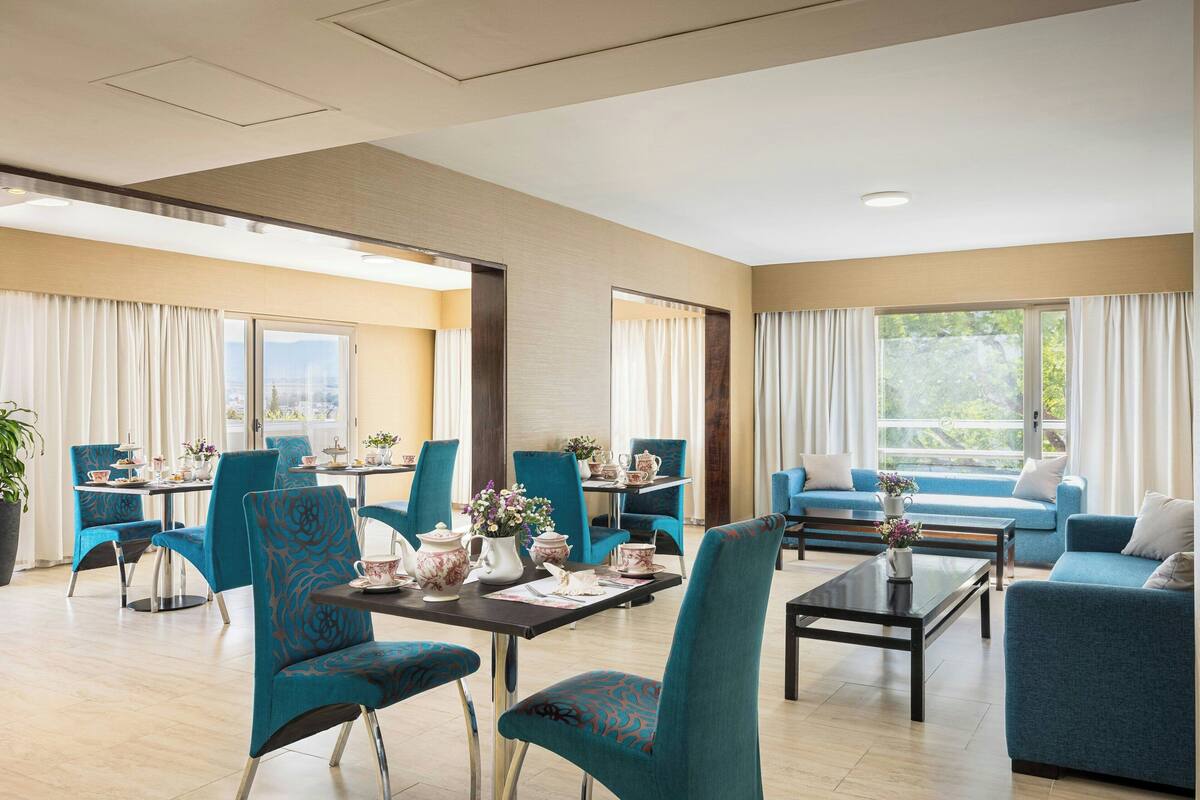 Um quarto espaçoso com área de refeições, cadeiras estofadas em azul, uma mesa de centro e um sofá.